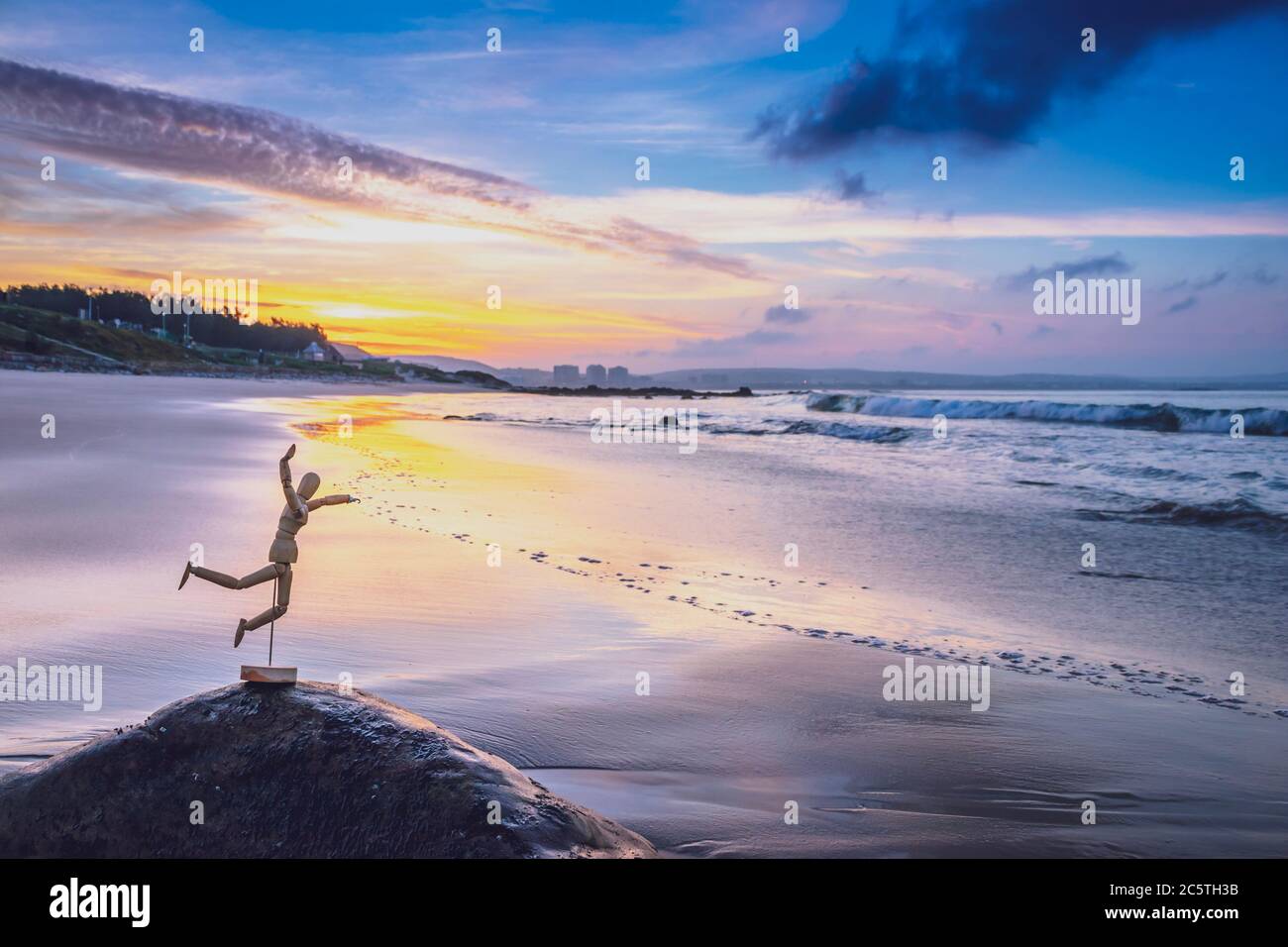 Wooden Human Manikin posing on beach with a view of a beautiful cloudy ...