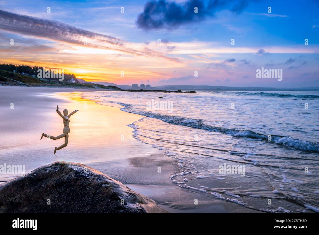 Wooden Human Manikin posing on beach with a view of a beautiful cloudy ...