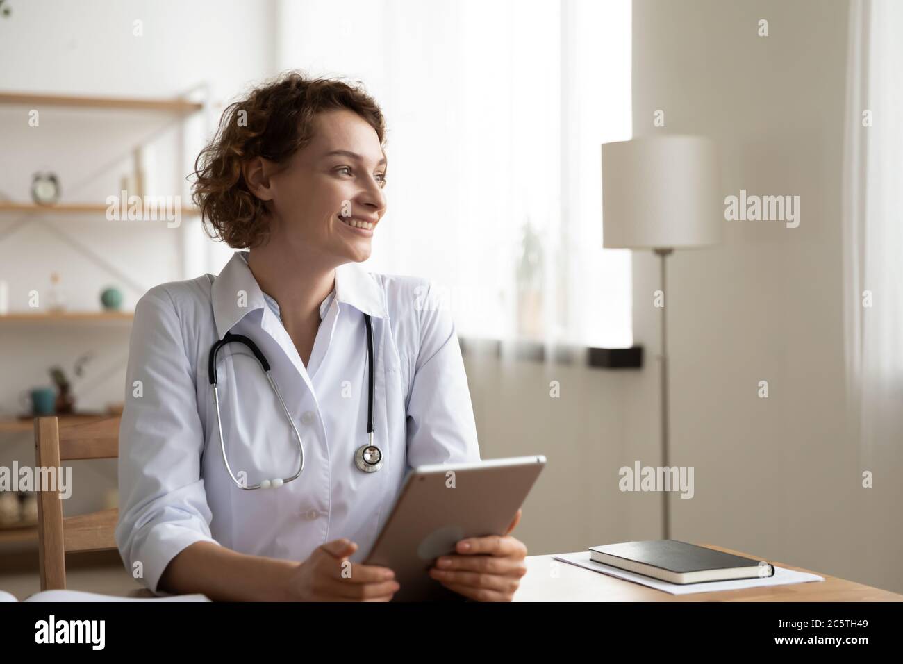 Smiling female doctor look in distance dreaming Stock Photo - Alamy