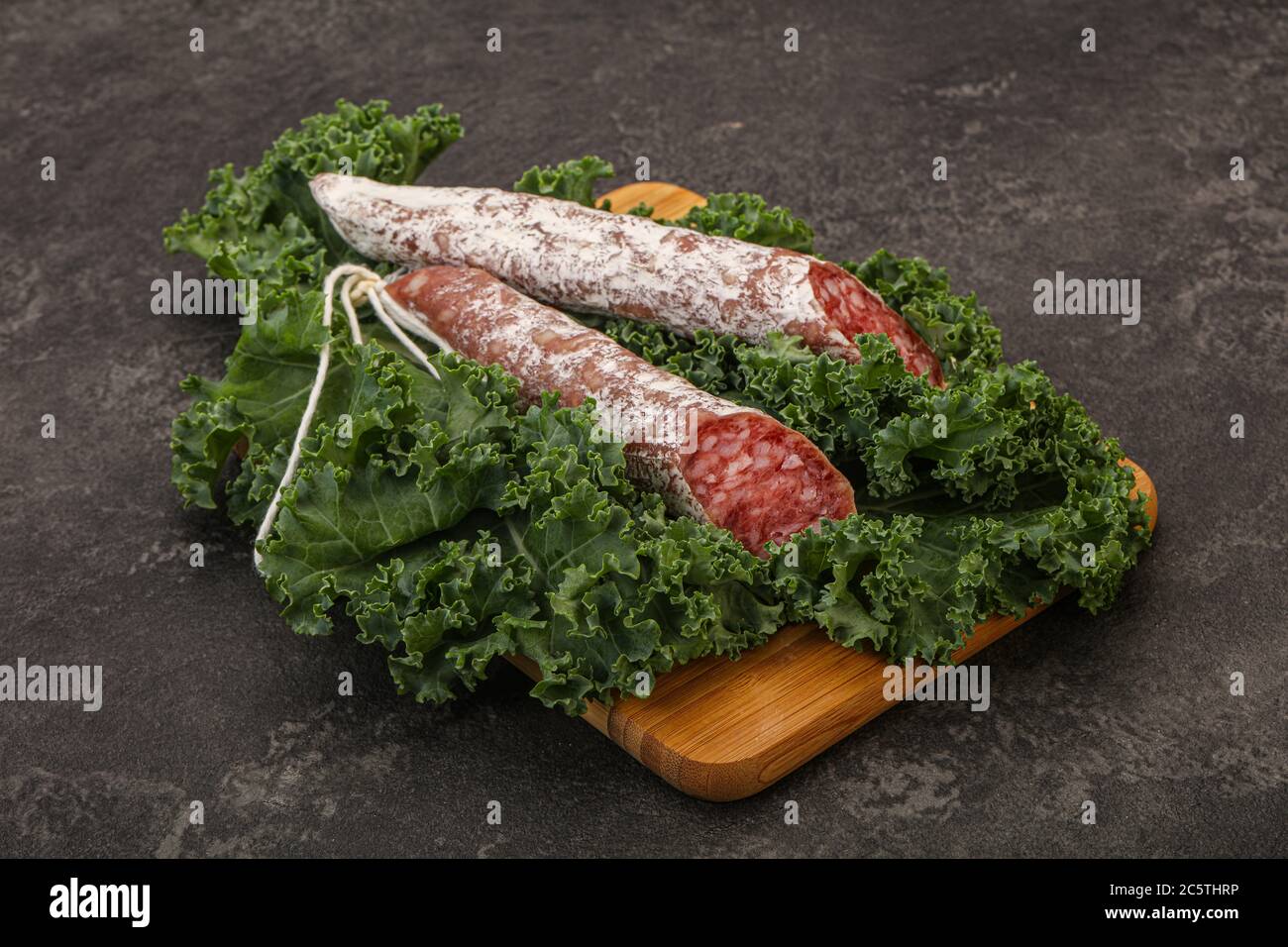 Spanish Fuet sausage with salad leaves over wooden background Stock ...
