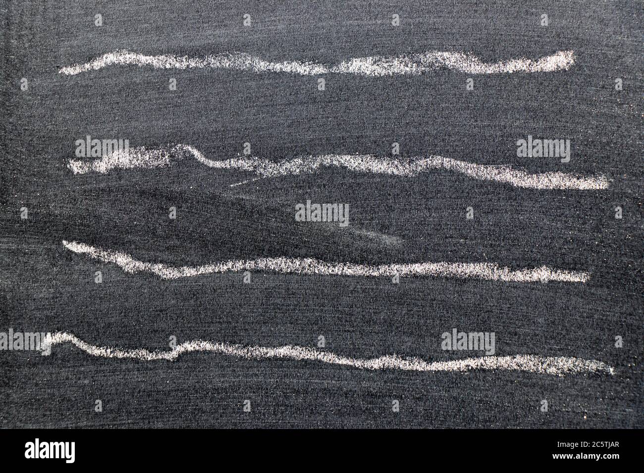 White color chalk hand drawing in set of wavy line shape on black board ...