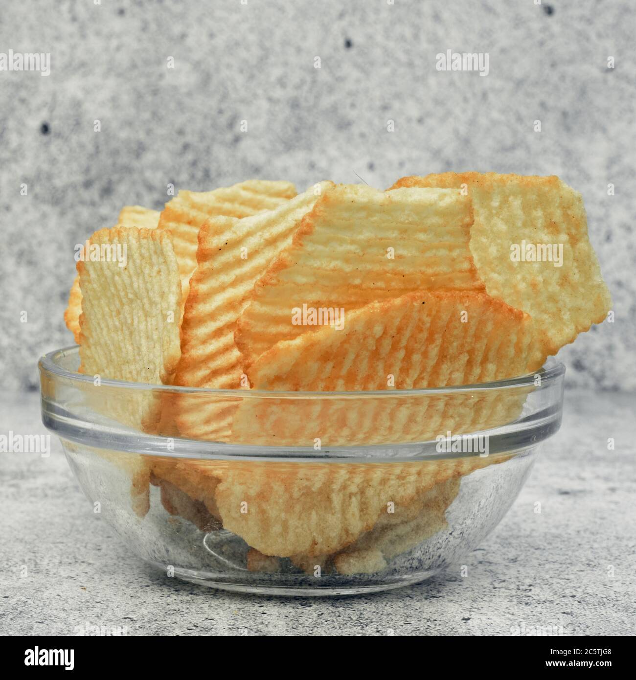 Corrugated potato chips in a slack transparent plate. Snack, junk food ...