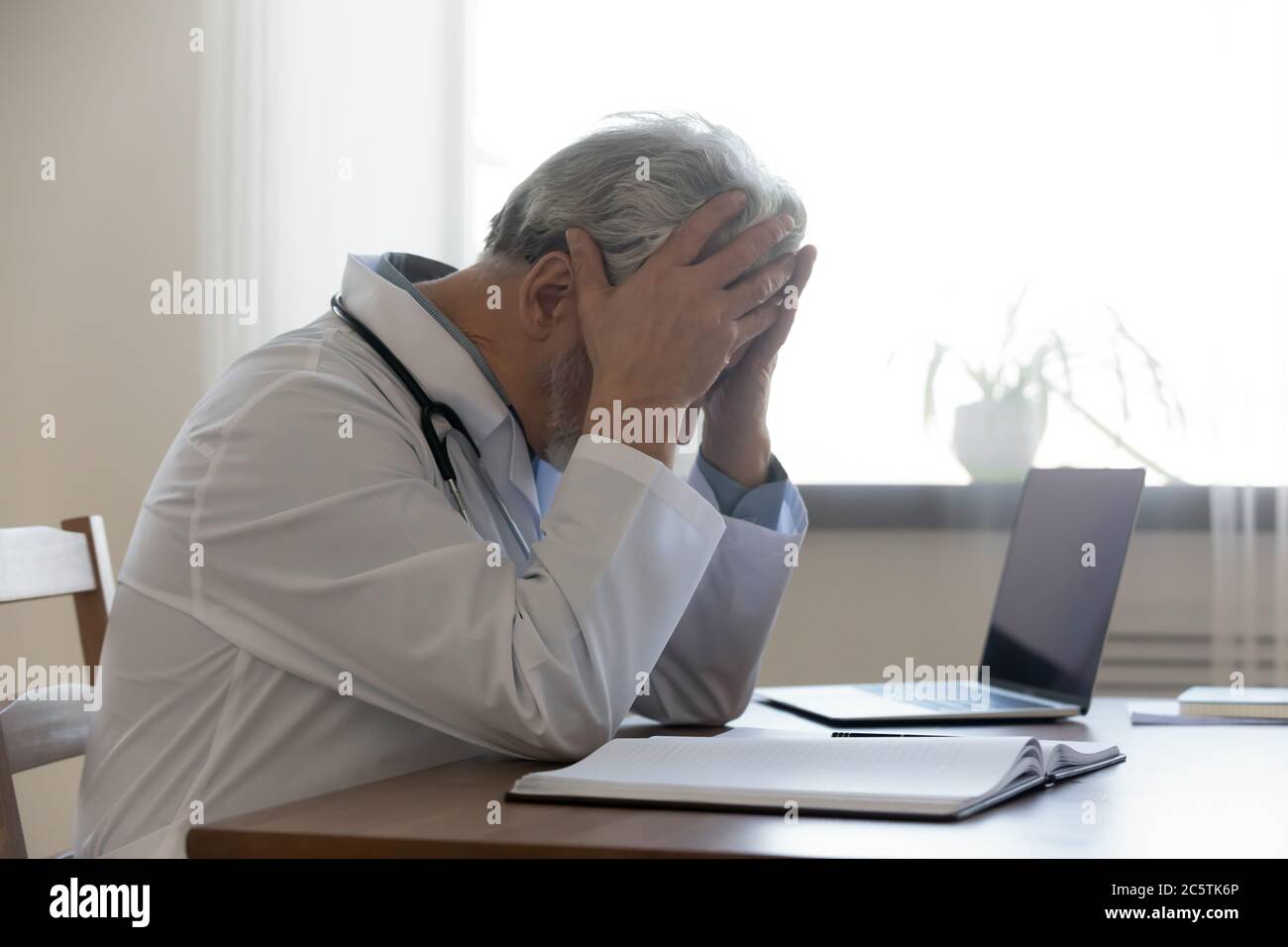 Distressed mature male doctor stressed with work Stock Photo - Alamy
