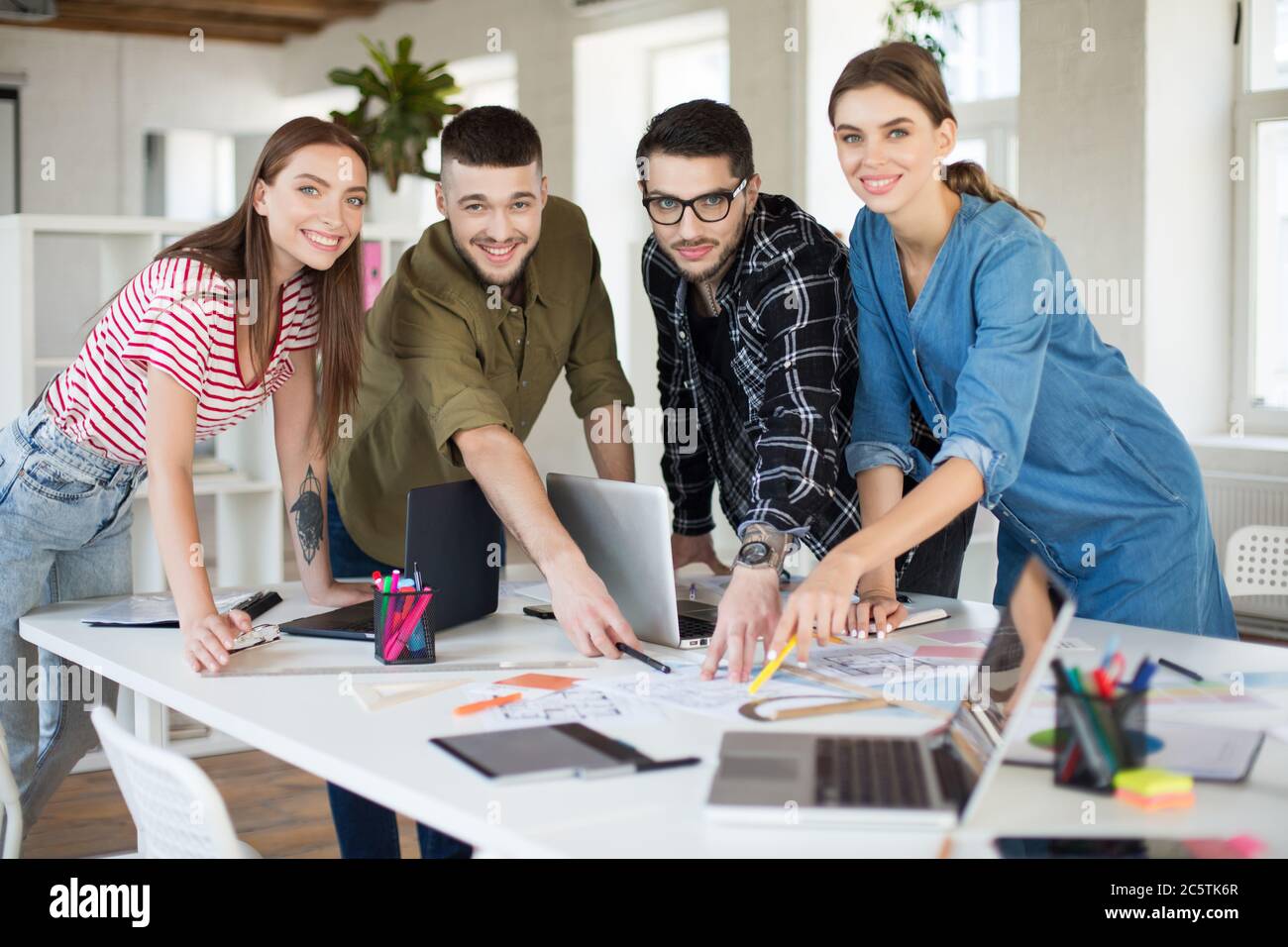 Young smiling creative people happily looking in camera working ...