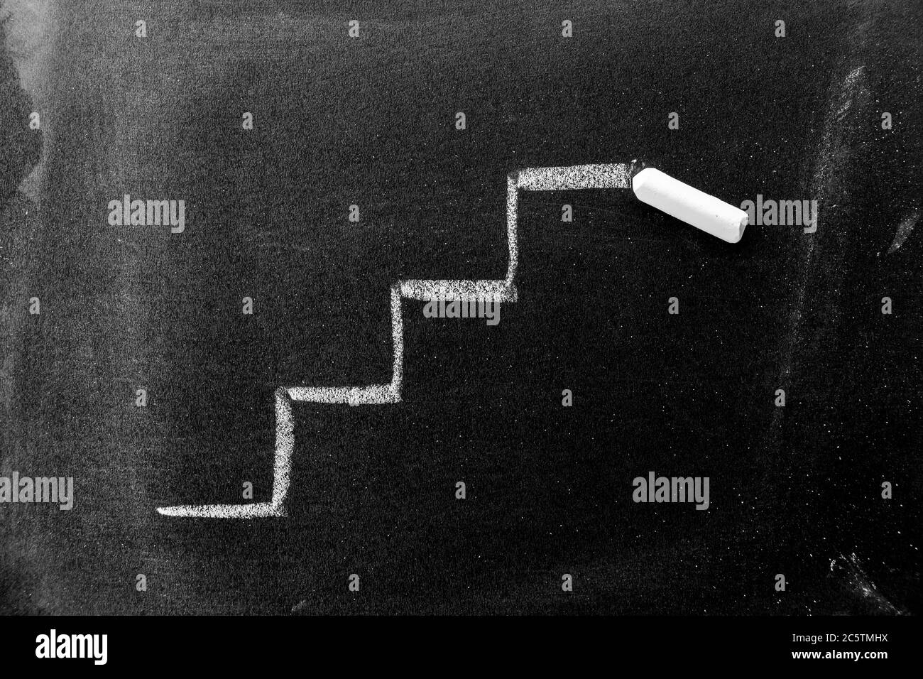 White color chalk hand drawing in staircase shape on black board ...