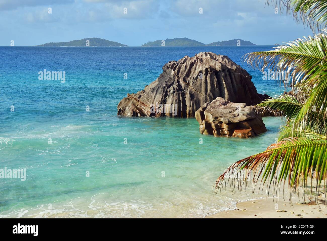 Beautiful landscape with granite boulders in the ocean and palm tree ...
