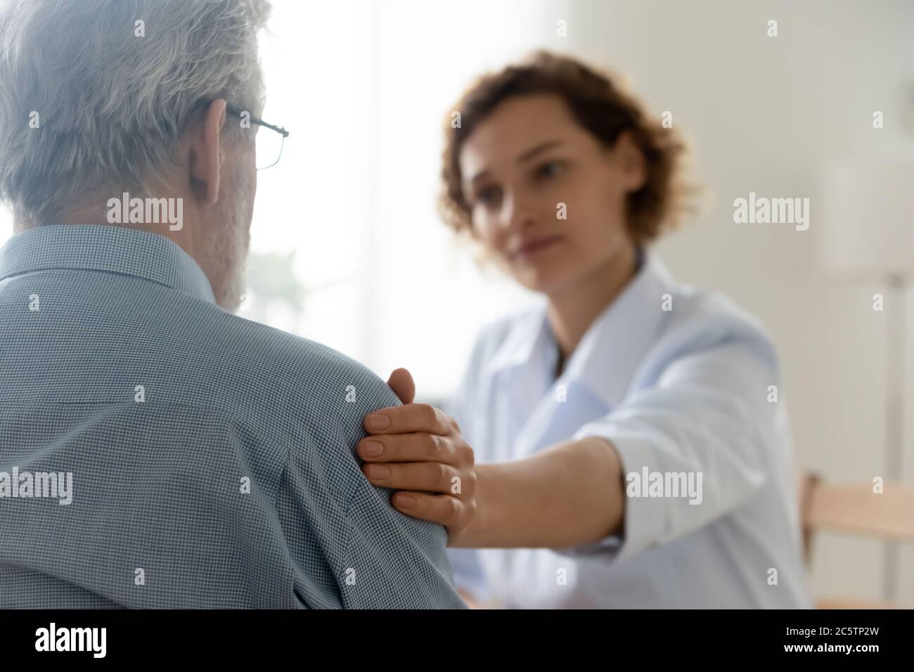 Caring female doctor comfort senior male patient at consultation Stock ...
