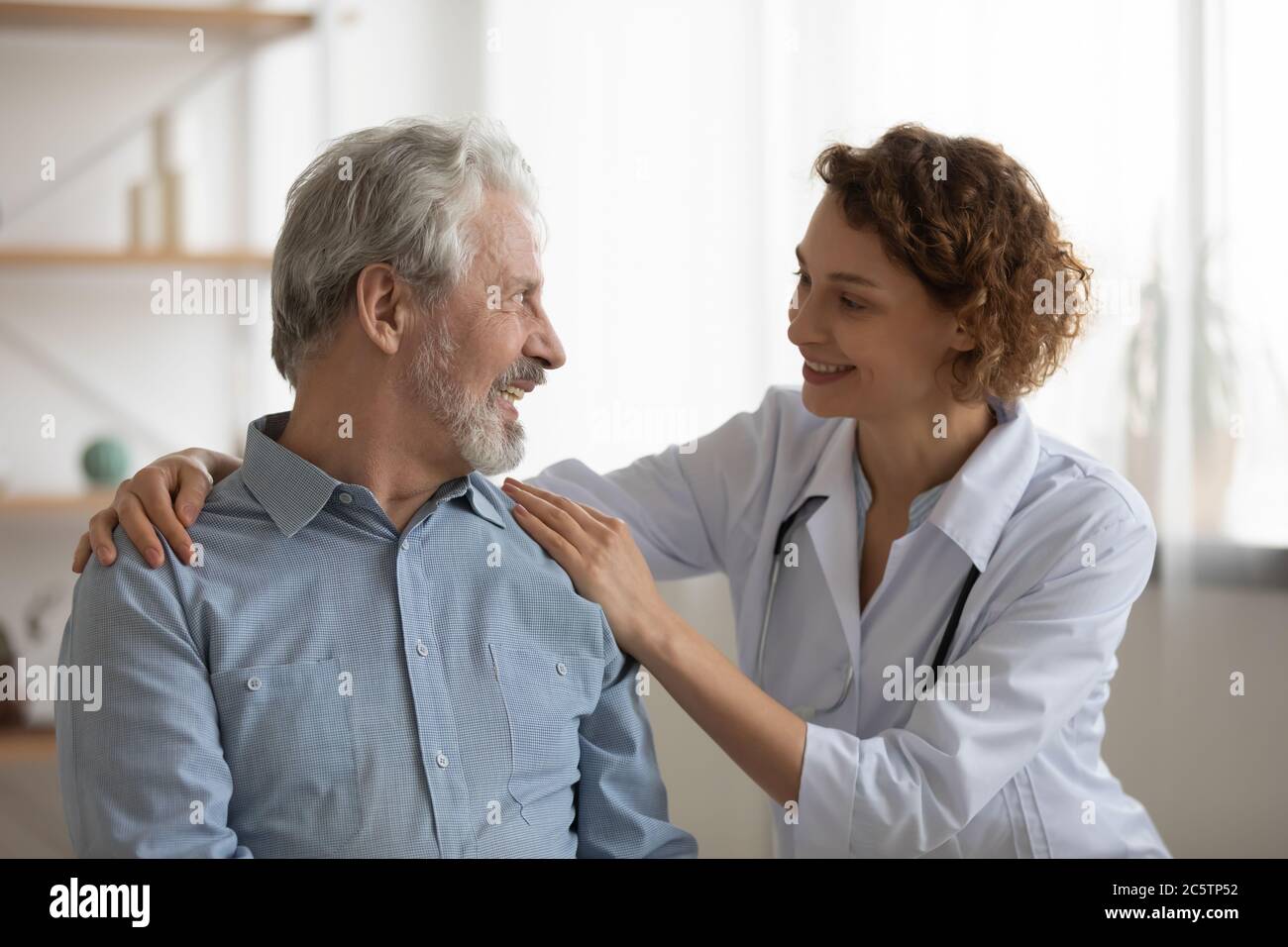 Caring woman doctor comfort elderly male patient Stock Photo - Alamy