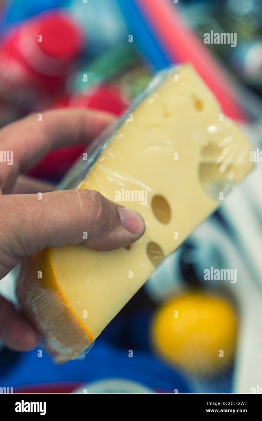 Male hand holds cheese in a supermarket. vertical photo toned Stock ...