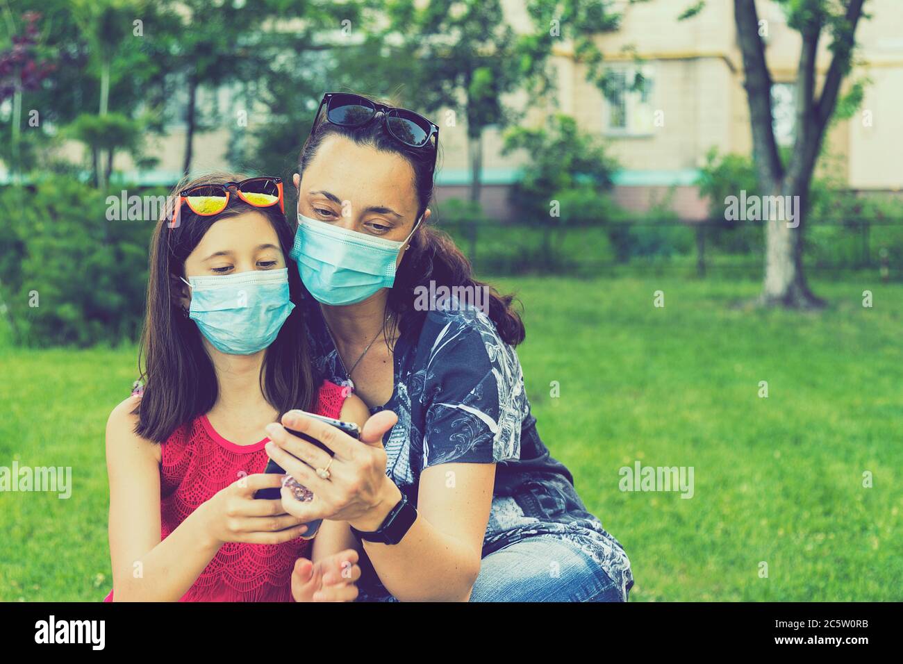Mom with daughter in the park in medical masks. Family of mom and kid ...