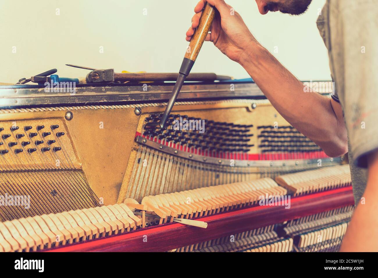 Piano tuning process. closeup of hand and tools of tuner working on ...