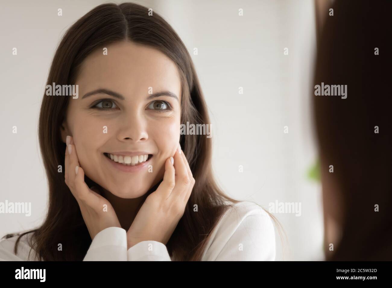 Mirror reflection head shot smiling woman touching healthy smooth skin ...