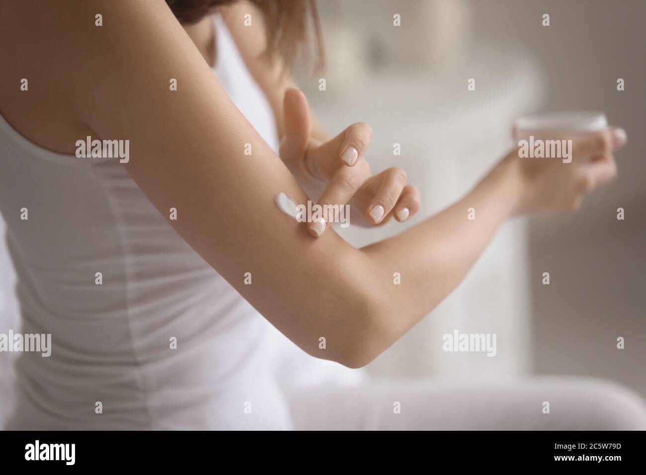 Close up young woman applying moisturizing cream on arm Stock Photo - Alamy