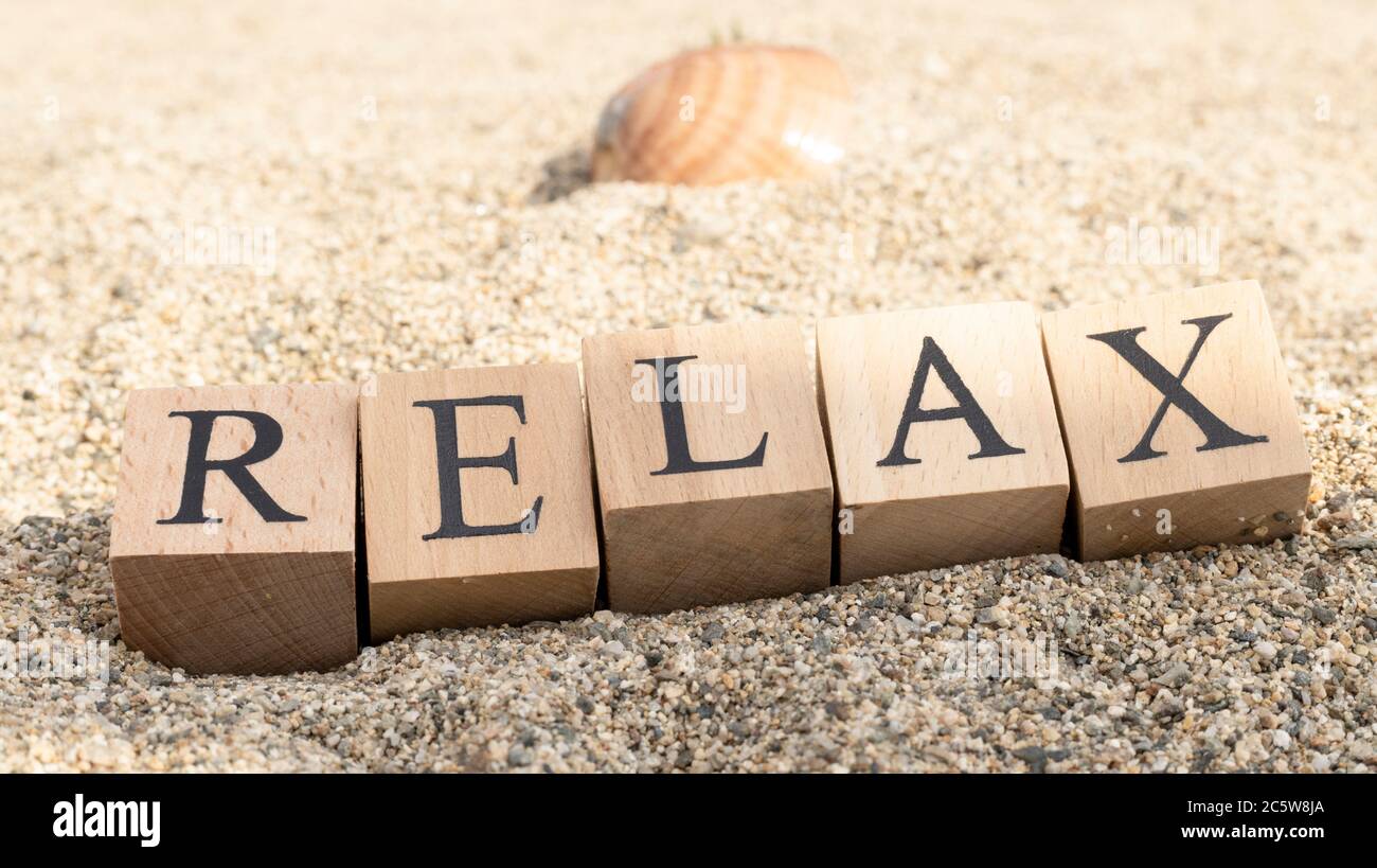 The word relax from wooden cubes. Close-up on the beach sand Stock ...