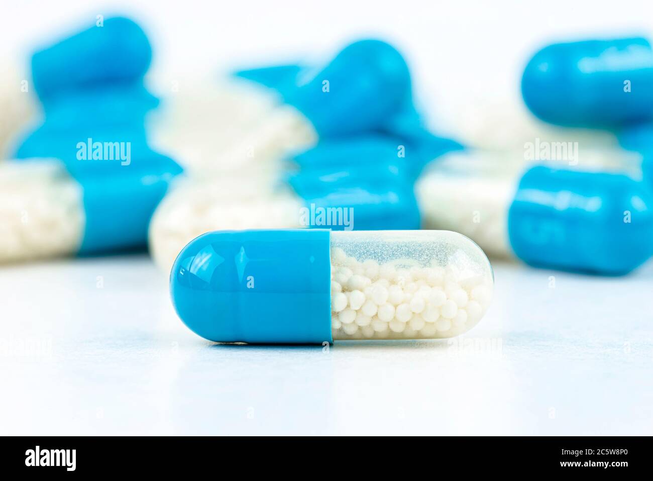 Blue gelatin capsules with white granules inside, isolated on a white ...