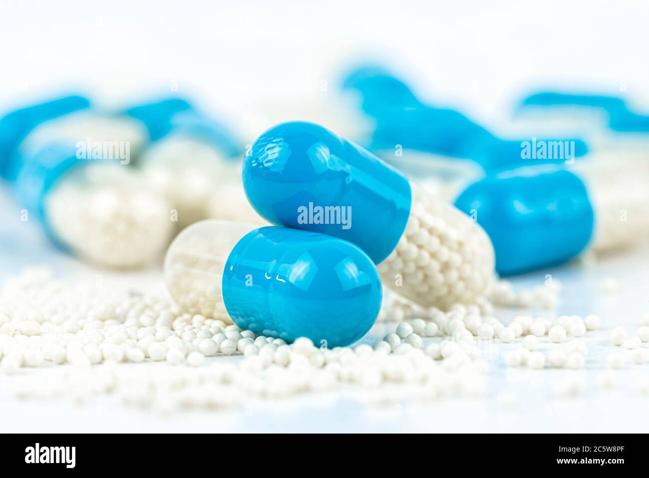 Blue gelatin capsules with white granules inside, isolated on a white ...