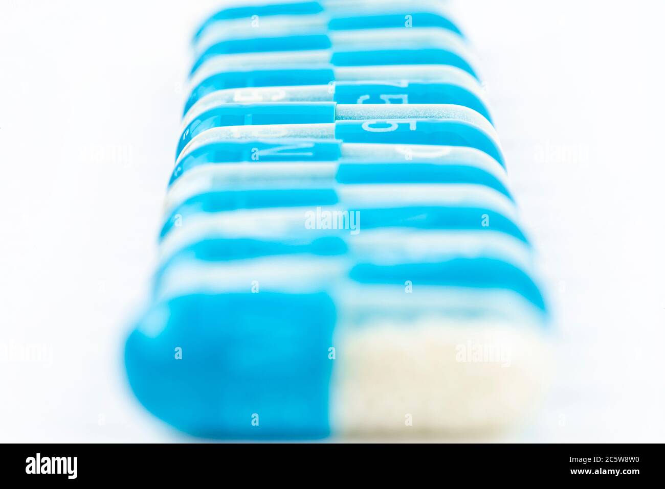 Blue gelatin capsules with white granules inside, isolated on a white ...