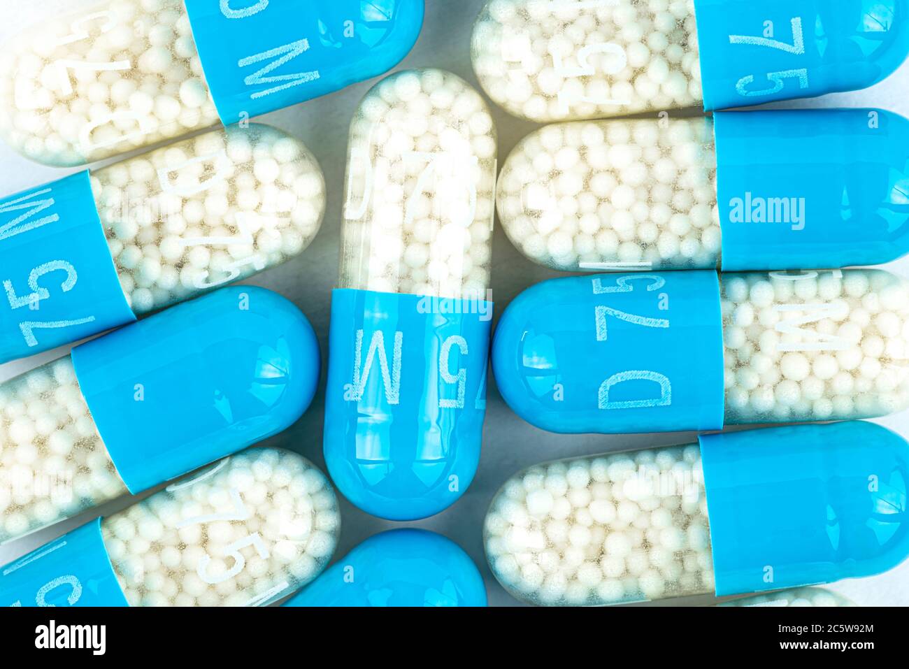 Blue gelatin capsules with white granules inside, isolated on a white ...