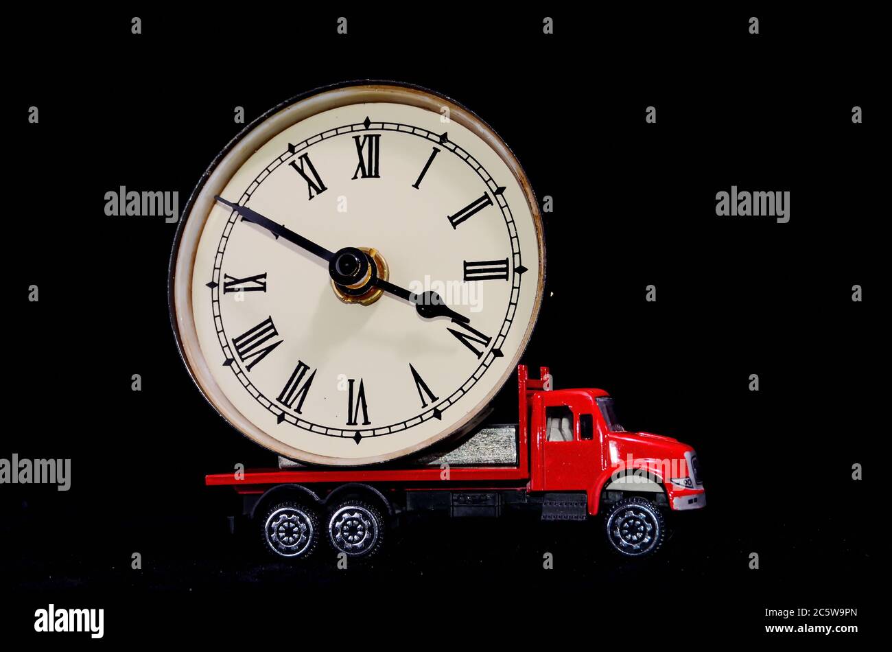Time Transportation Concept Clock Watch on a Red Toy Truck over Black ...