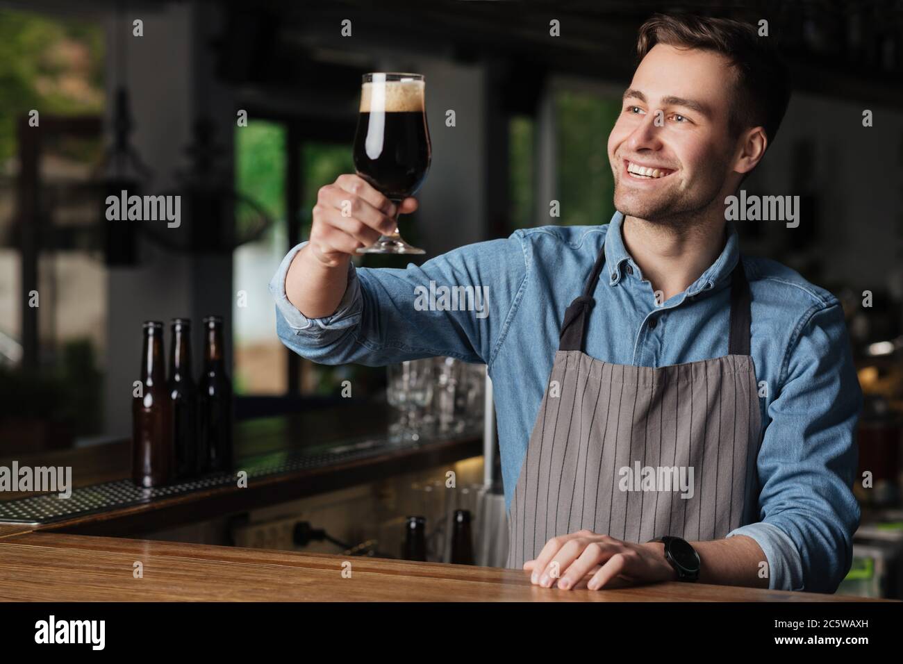 Top grade. Smiling bartender enjoying dark beer in hand Stock Photo - Alamy