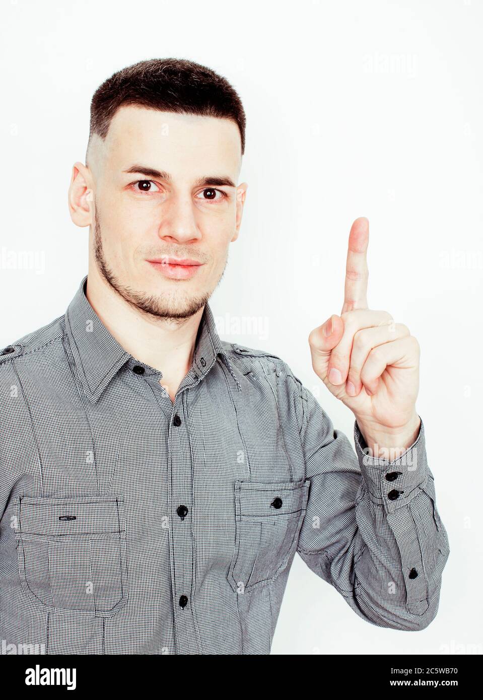 Portrait of a smart serious young man standing against white background ...