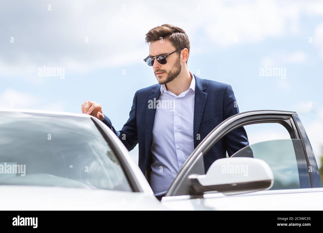 Serious young entrepreneur getting into his car in heart of city Stock ...