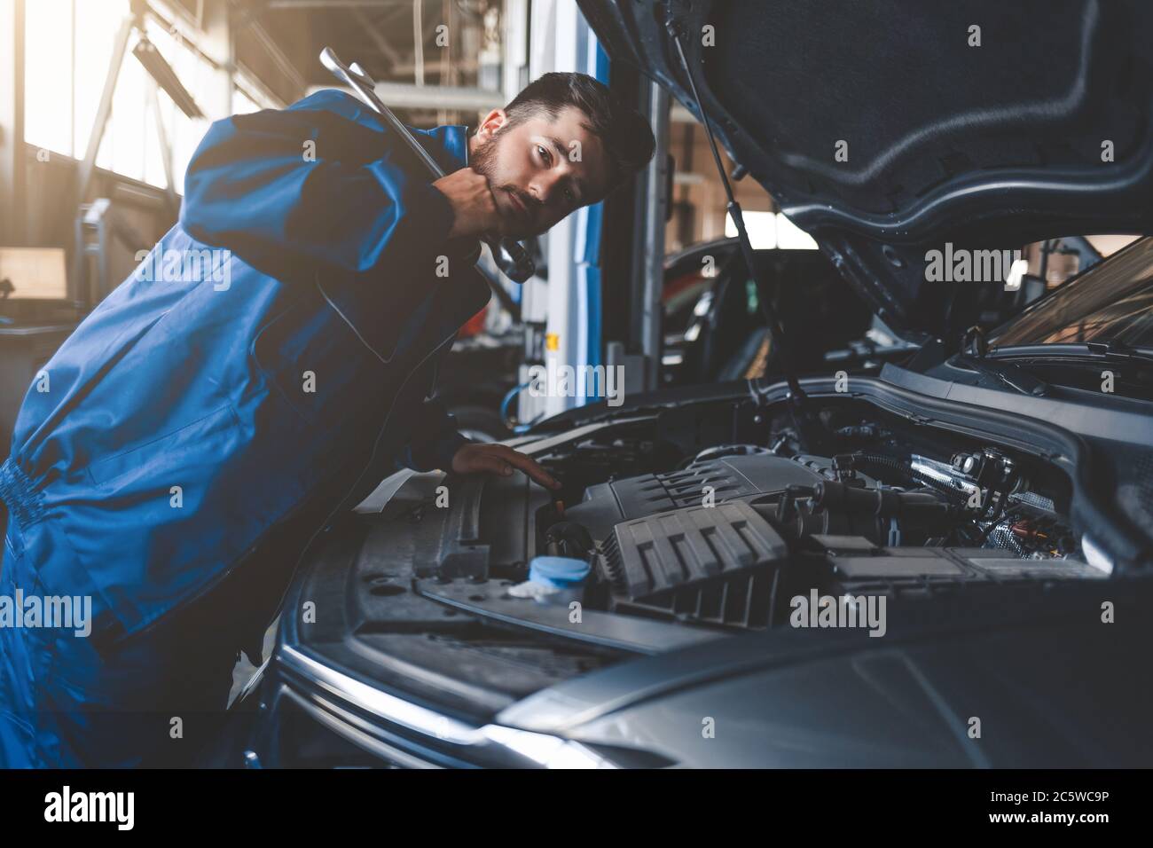 Auto mechanic with wrench over car hood. Car repairman in the service ...