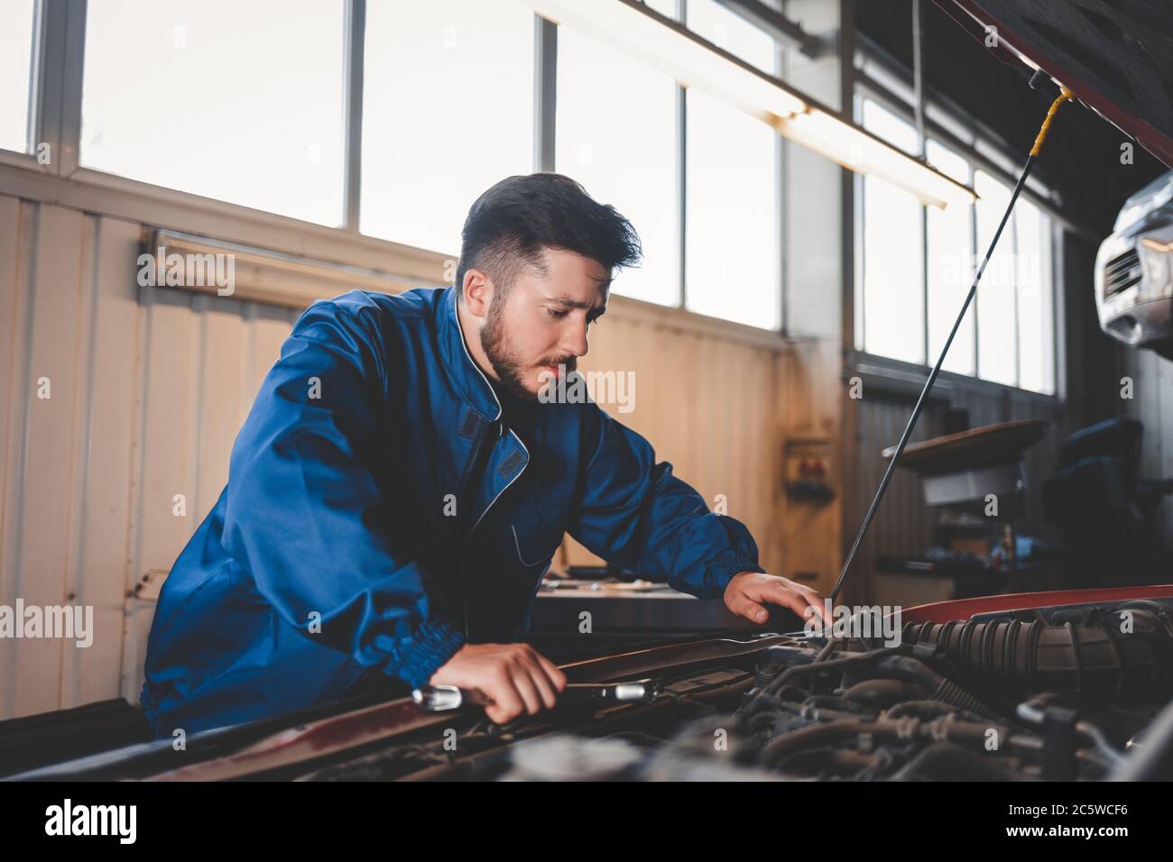 Pensive auto mechanic looking for engine malfunction problem. Car ...