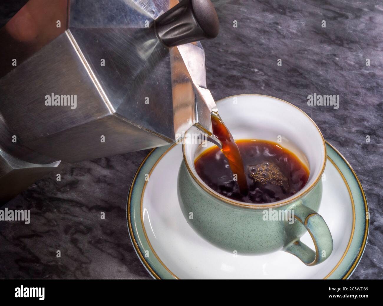 Closeup of freshly brewed, hot dark coffee, pouring from a traditional ...