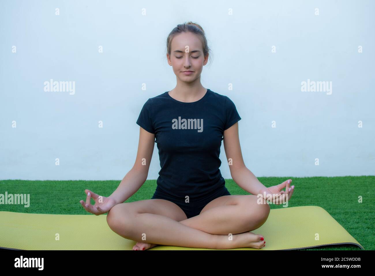 Pretty girl on the grass doing yoga stretches Stock Photo - Alamy