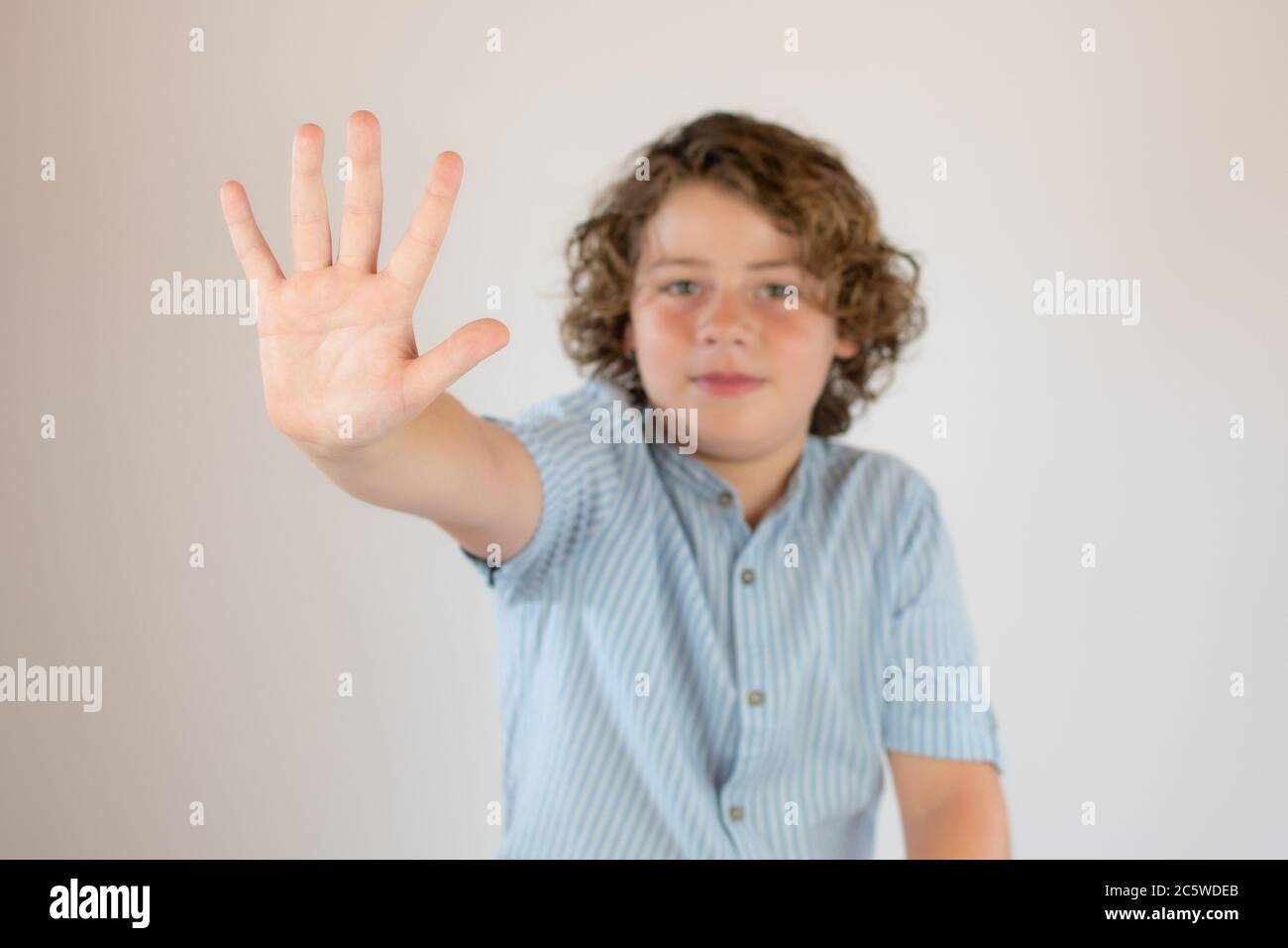 Boy with blue shirt smiling and making stop gesture Stock Photo - Alamy