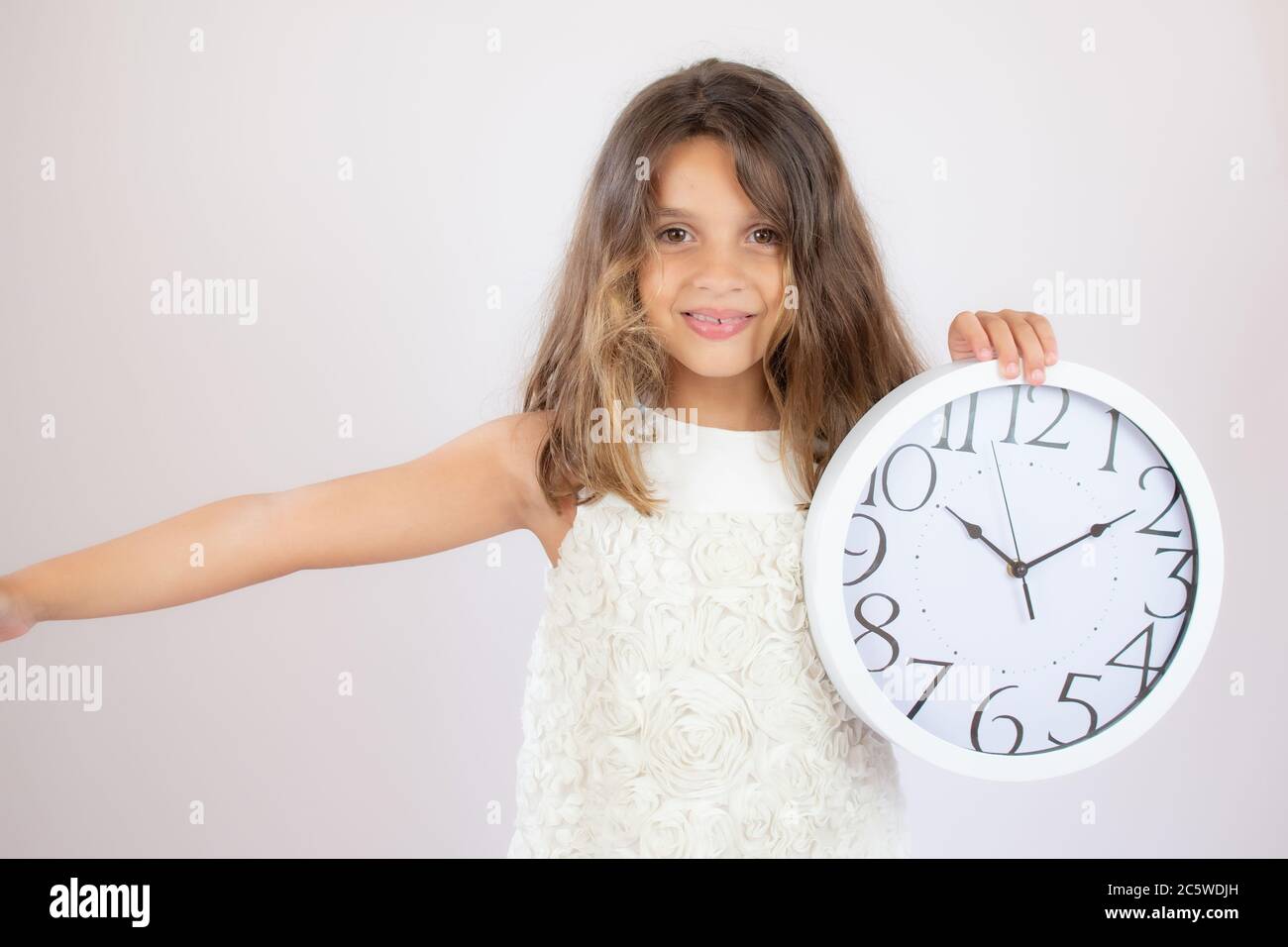 Beautiful girl smiling showing a clock Stock Photo - Alamy
