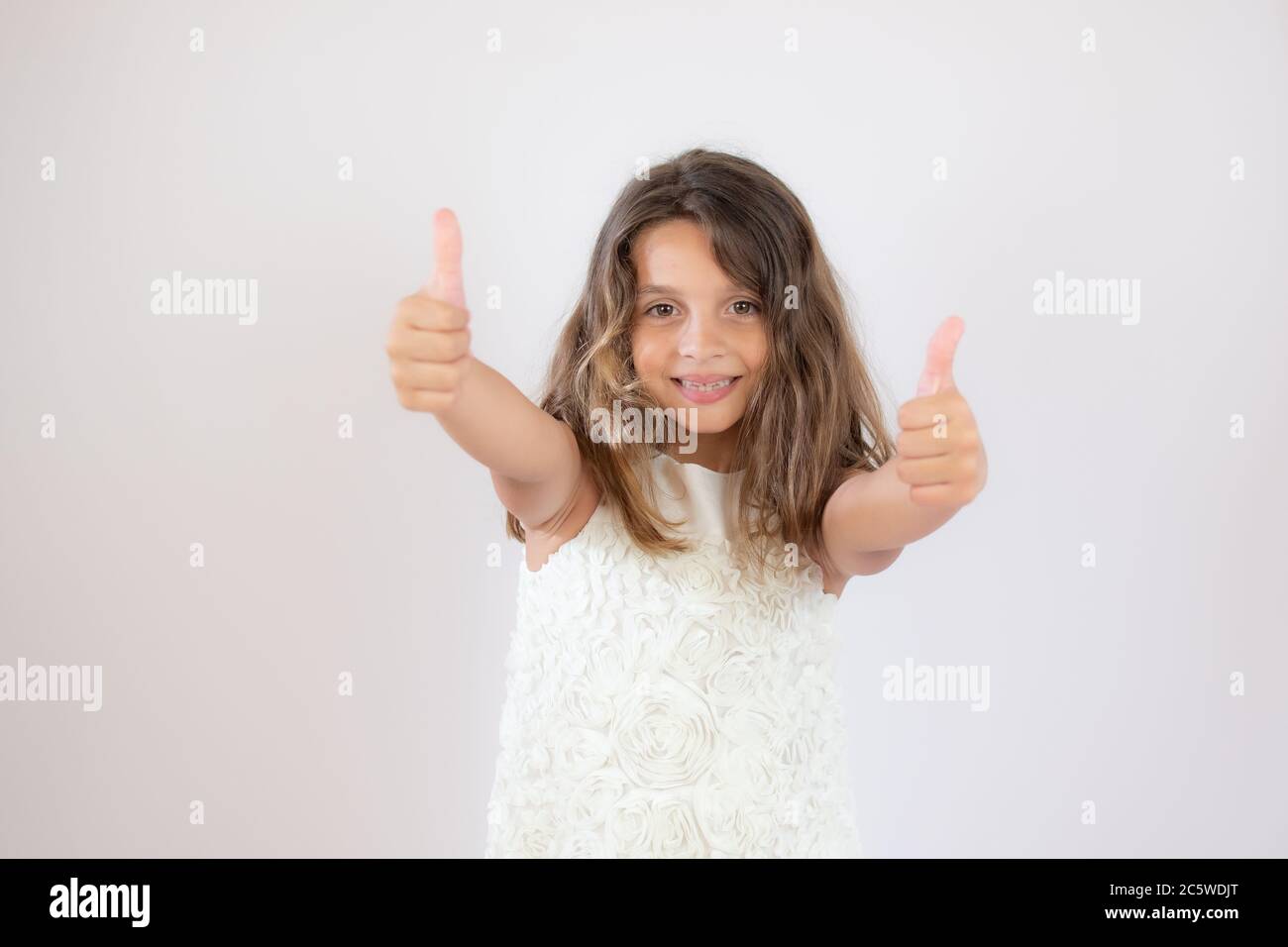 Beautiful little girl making fingers up gesture Stock Photo - Alamy