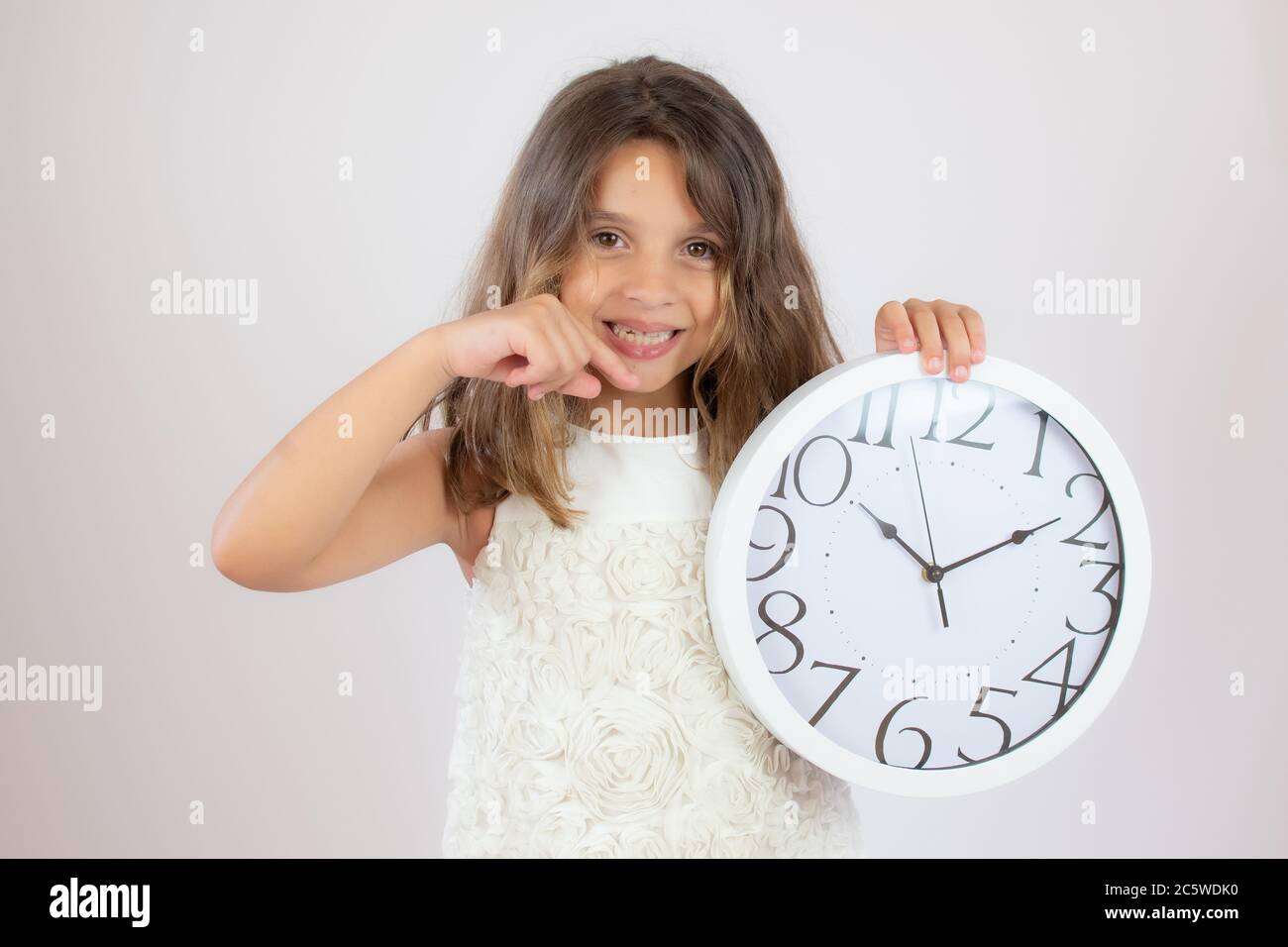 Beautiful girl smiling showing a clock Stock Photo - Alamy