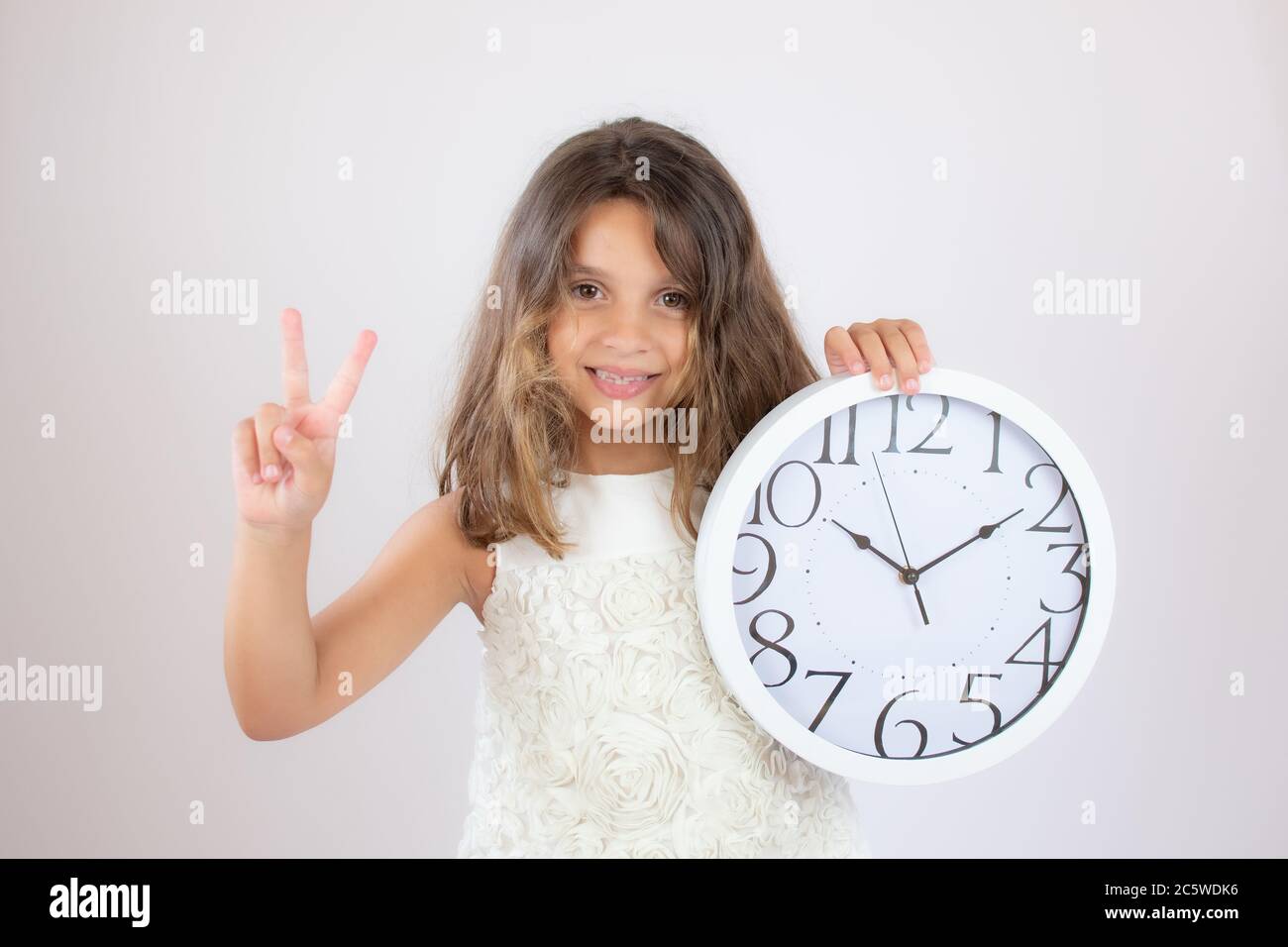 Beautiful girl smiling showing a clock Stock Photo - Alamy