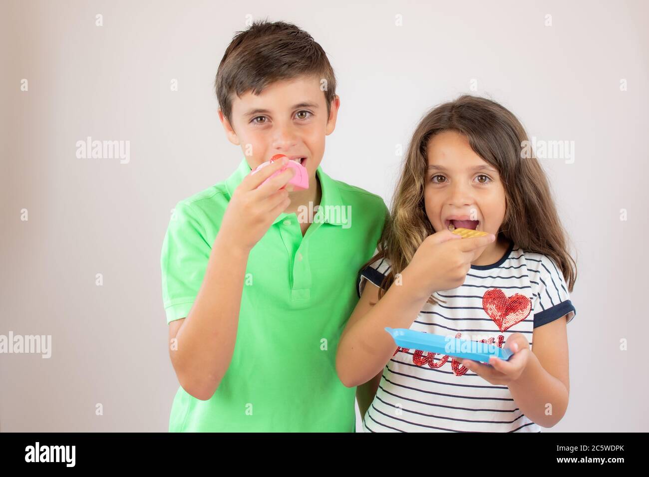 Two friends in a birthday party eating cake smiling Stock Photo - Alamy