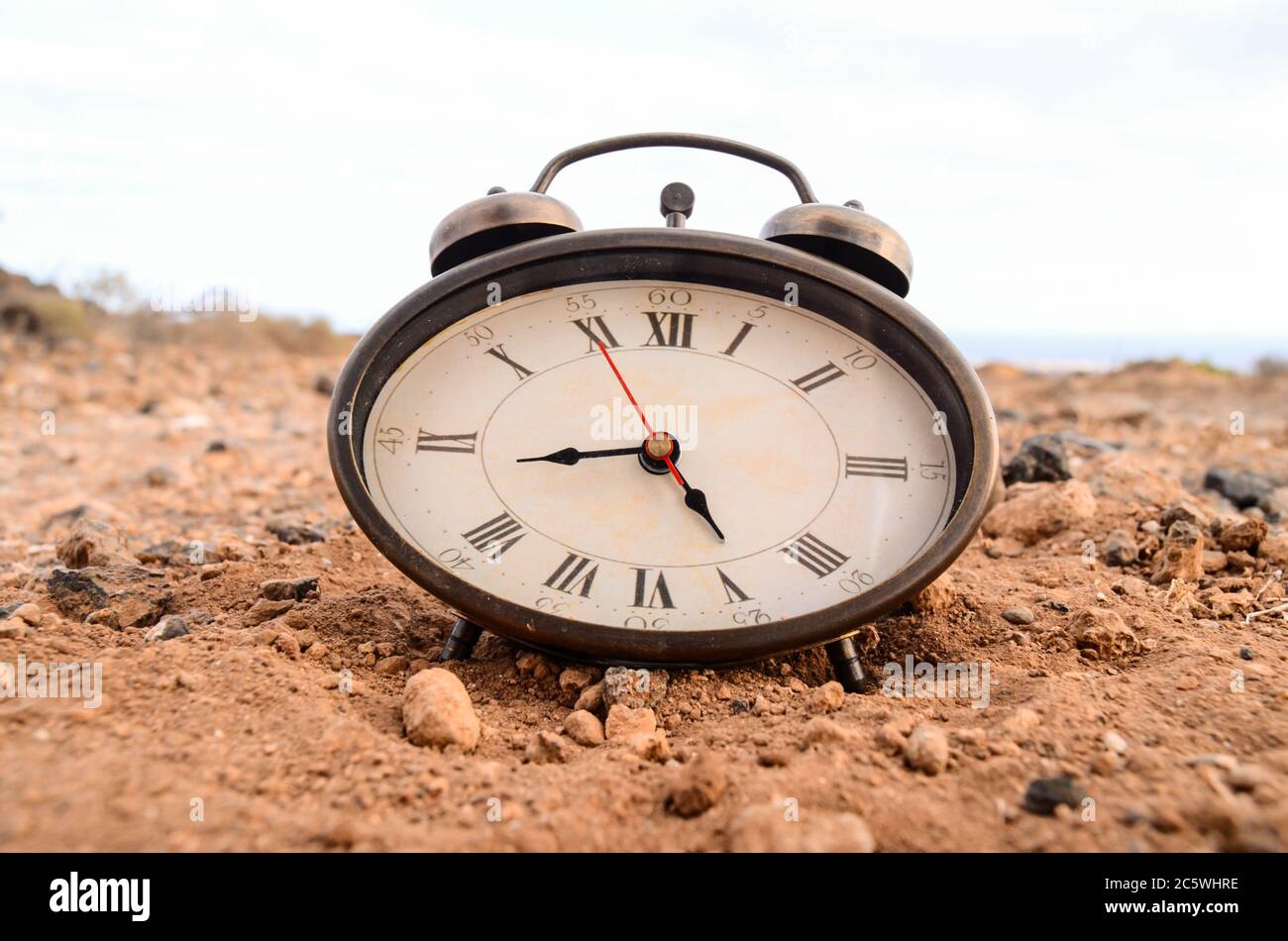 Classic Analog Clock In The Sand On The Rock Desert Stock Photo - Alamy