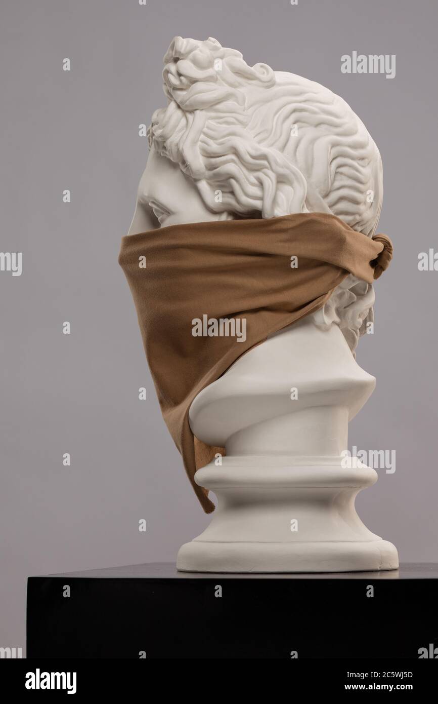 White plaster statue of a bust of Apollo Belvedere in a headscarf ...