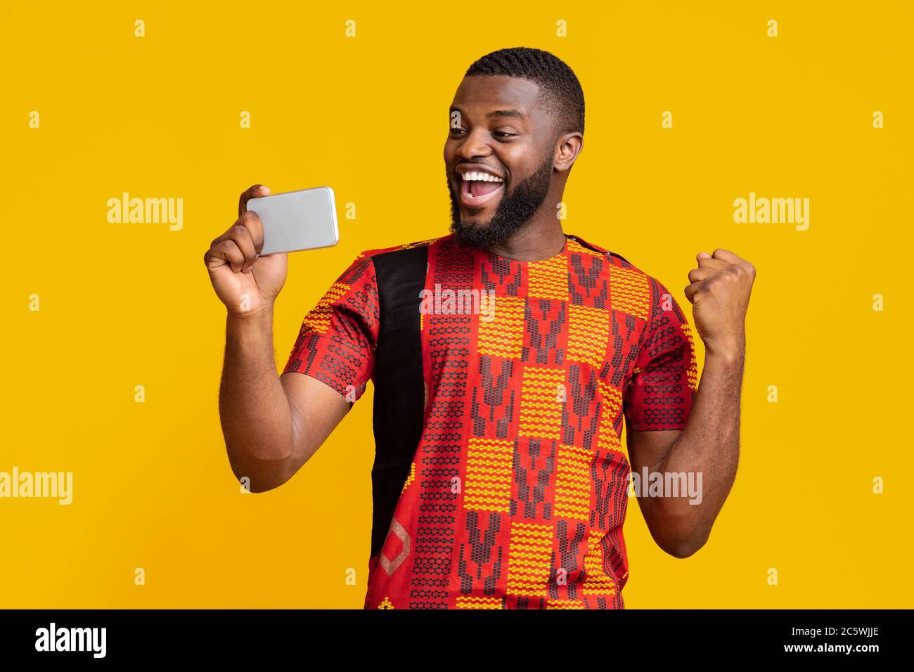 Happy black man holding phone and expressing happiness Stock Photo - Alamy