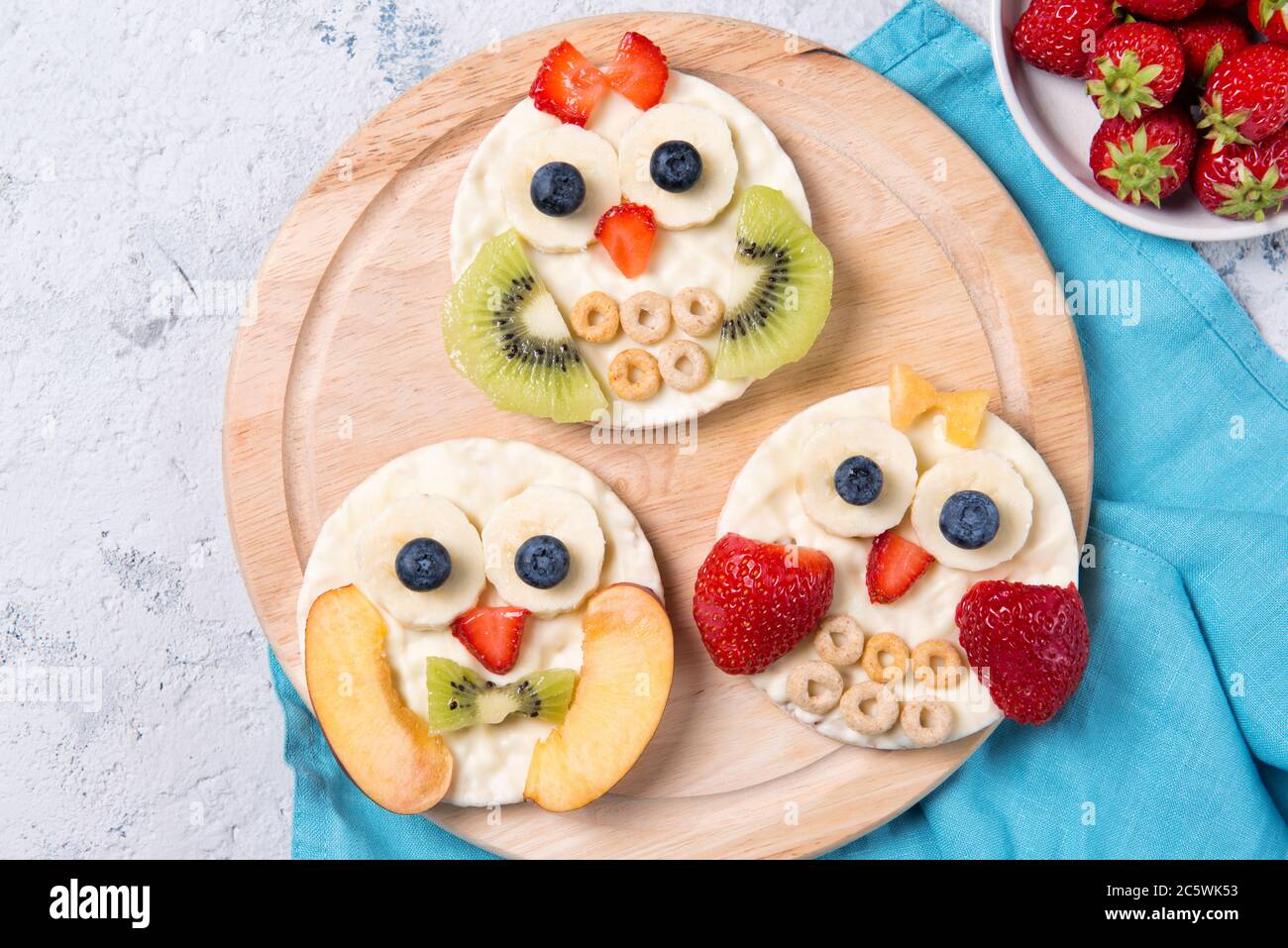 Rice cakes with yoghurt and fresh fruits in a shapes of cute owls on a ...