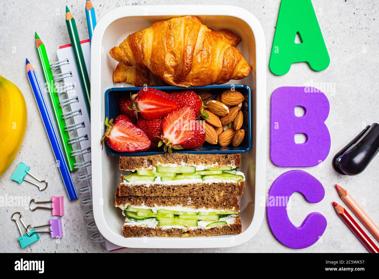 Back to school concept. Lunch box with a sandwich, croissants and ...