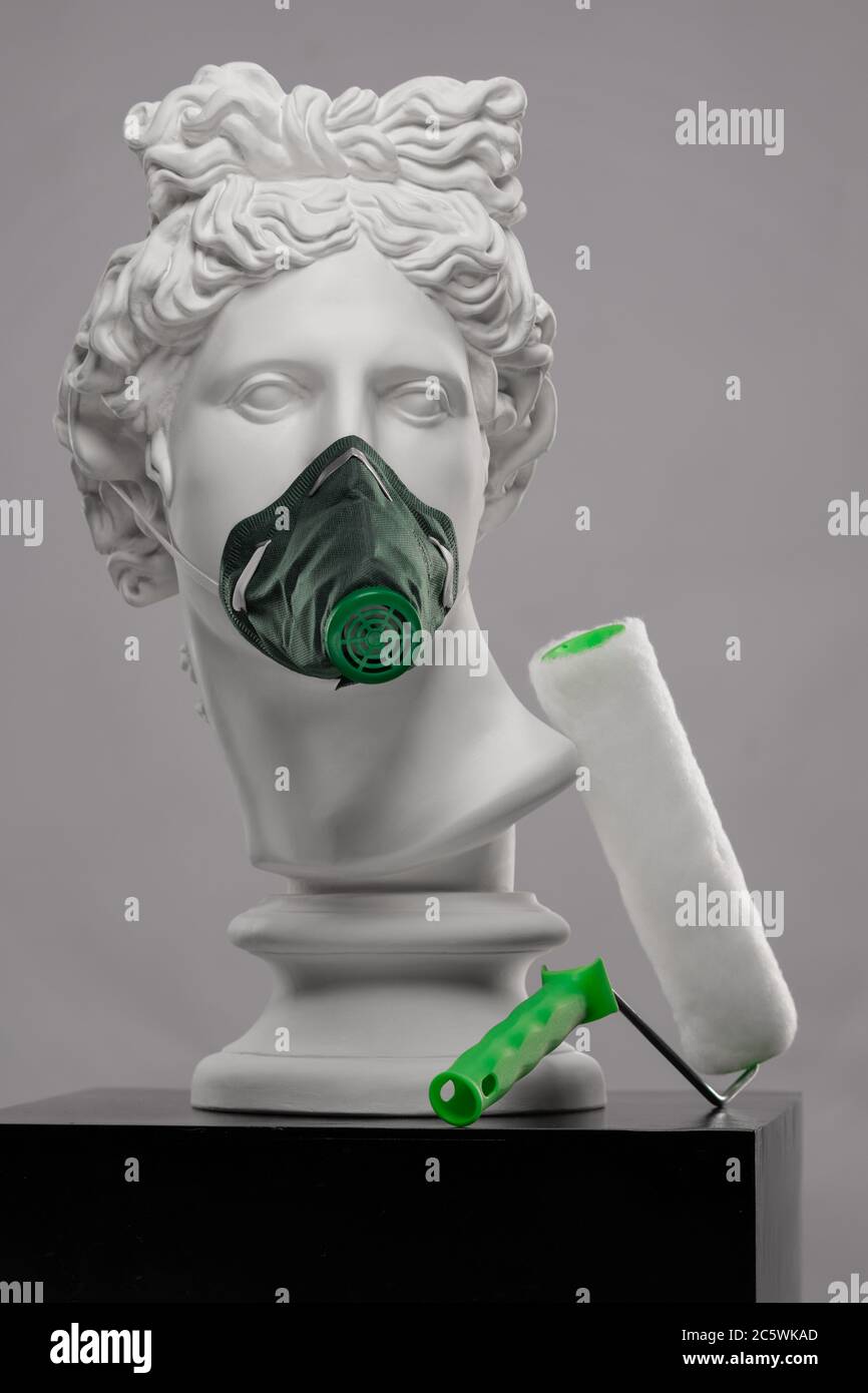 White plaster statue of a bust of Apollo Belvedere in a mask respirator ...