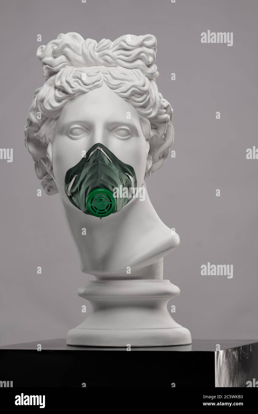 White plaster statue of a bust of Apollo Belvedere in a mask respirator ...