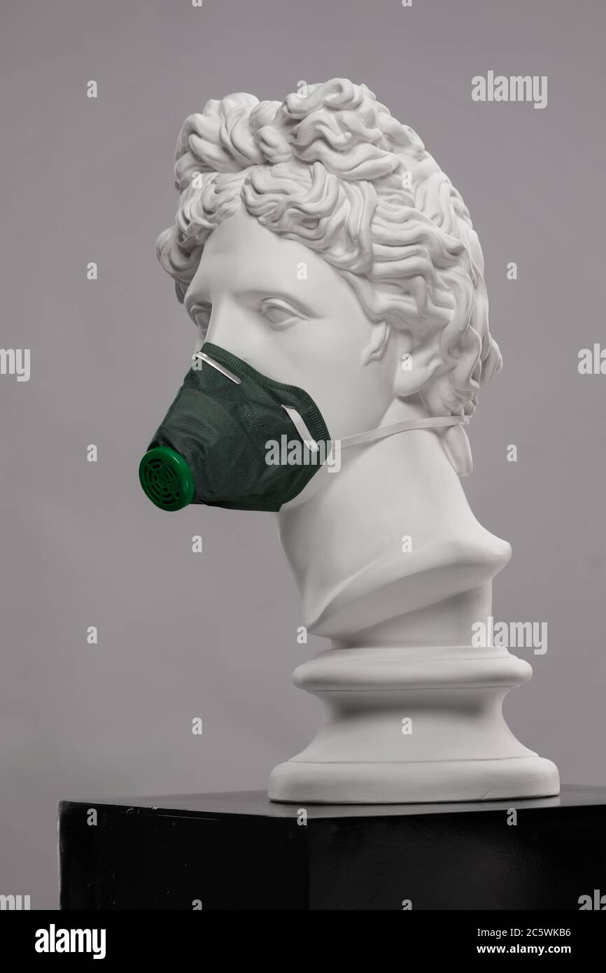 White plaster statue of a bust of Apollo Belvedere in a mask respirator ...