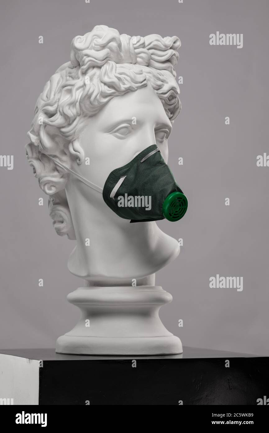 White plaster statue of a bust of Apollo Belvedere in a mask respirator ...