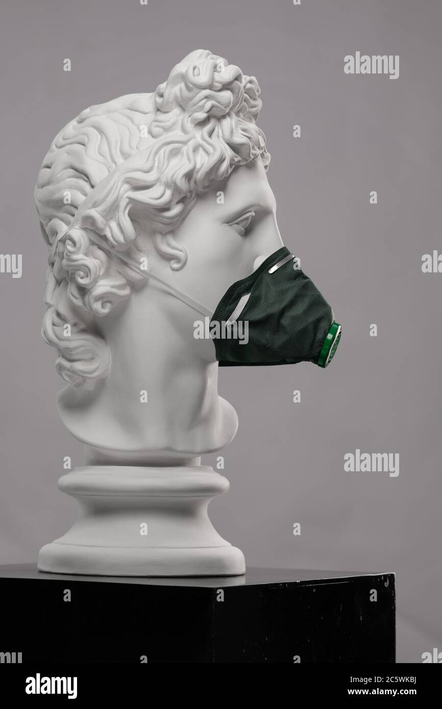 White plaster statue of a bust of Apollo Belvedere in a mask respirator ...