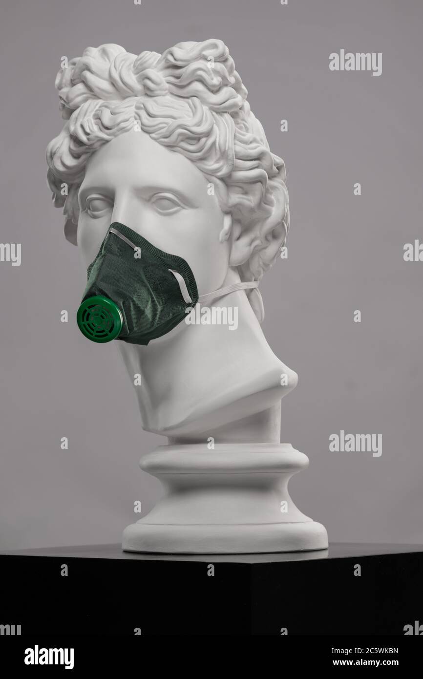 White plaster statue of a bust of Apollo Belvedere in a mask respirator ...