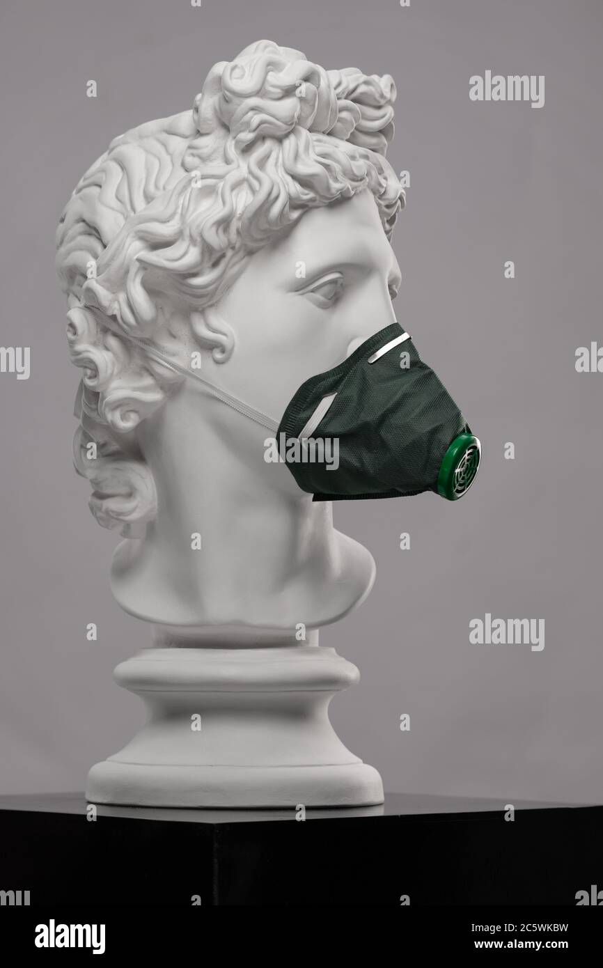 White plaster statue of a bust of Apollo Belvedere in a mask respirator ...