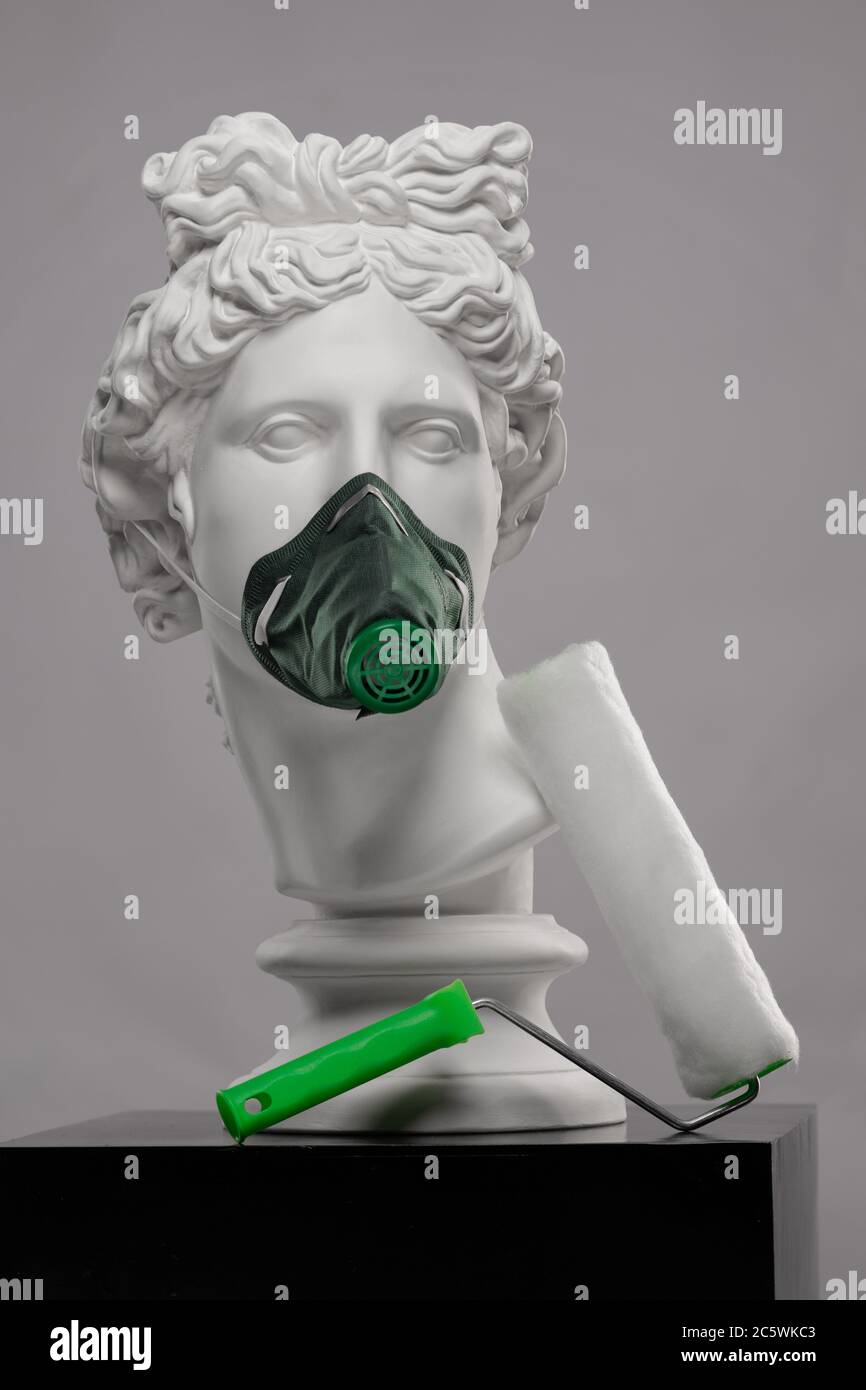 White plaster statue of a bust of Apollo Belvedere in a mask respirator ...