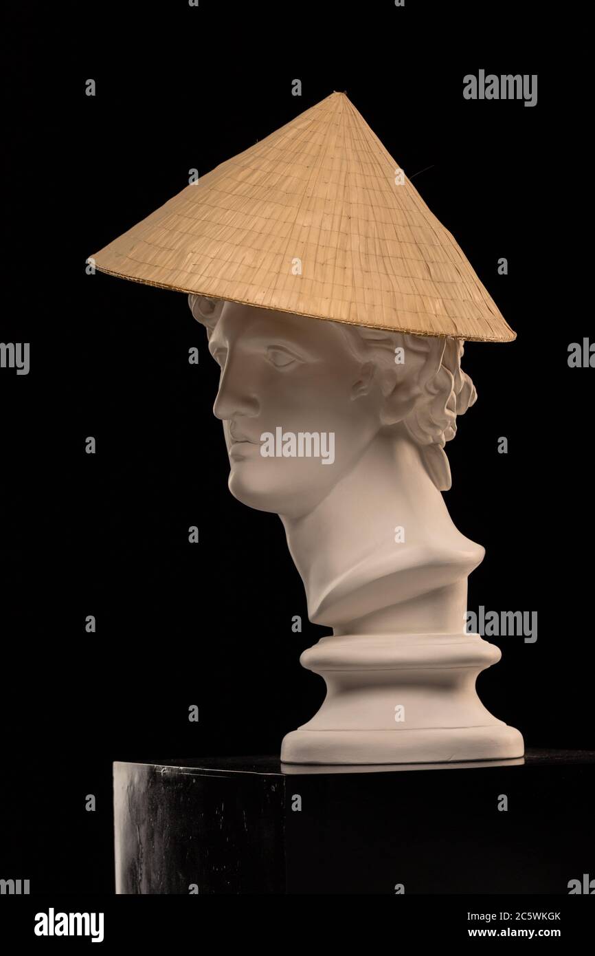 Statue of a bust of Apollo Belvedere in an Asian conical hat Stock ...
